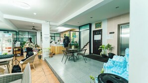 Um saguão de hotel moderno com balcão de recepção, área de estar e escadaria.