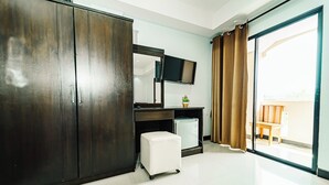 Quarto de hotel moderno com um guarda-roupa espaçoso, um frigorífico pequeno, uma televisão de ecrã plano e uma porta de vidro deslizante para uma varanda.