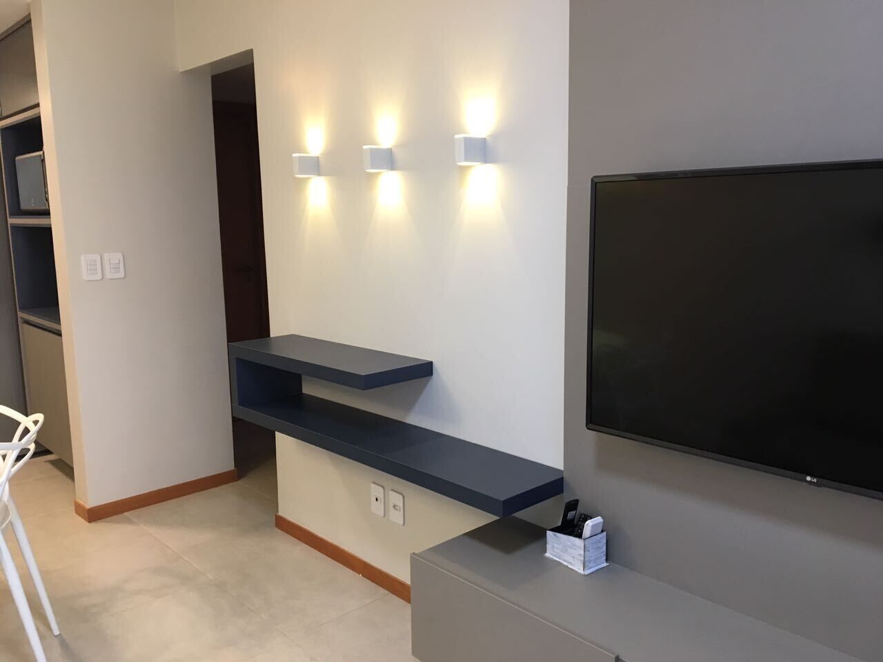 Uma sala de estar moderna com televisão de tela plana, prateleiras embutidas e iluminação embutida.