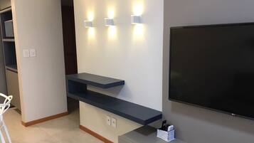 Uma sala de estar moderna com televisão de tela plana, prateleiras embutidas e iluminação embutida.