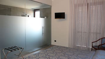 Um quarto com uma cama, guarda-roupa, televisão e uma cadeira.