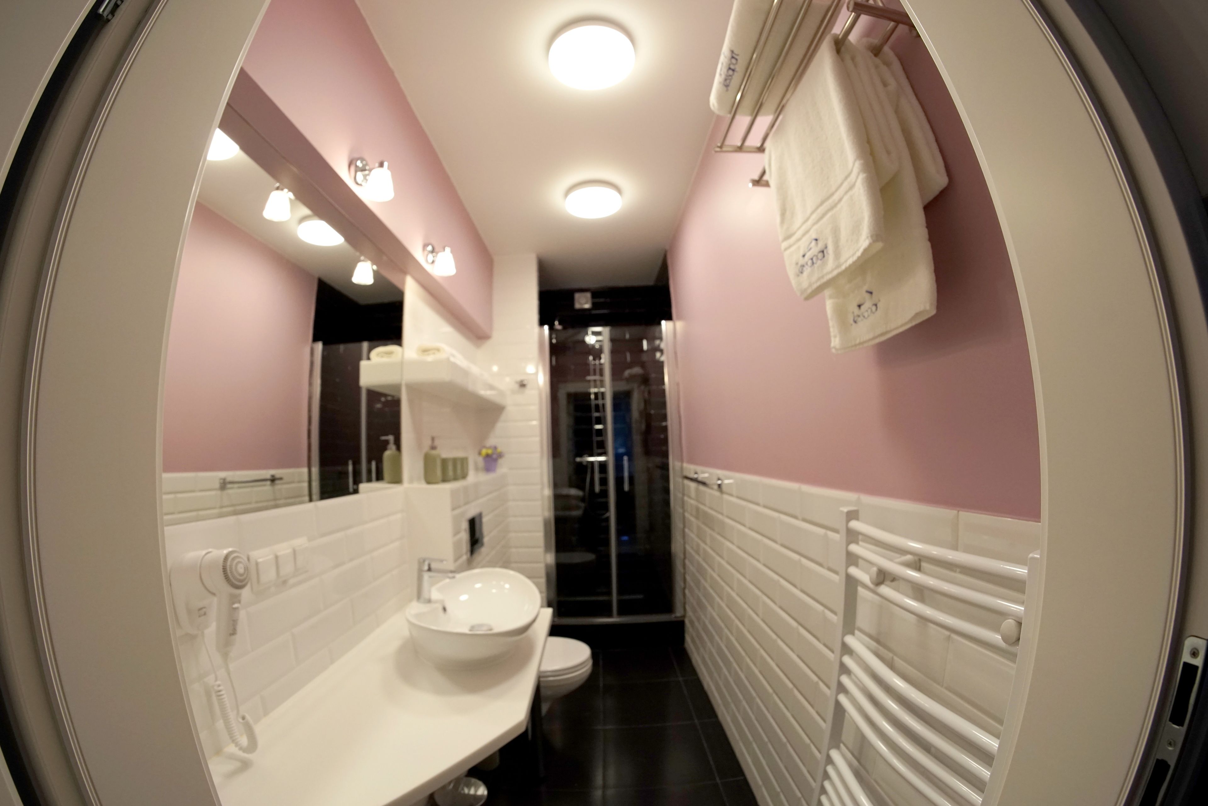 Casa de banho moderna com lavatório branco, espelho e porta-toalhas.