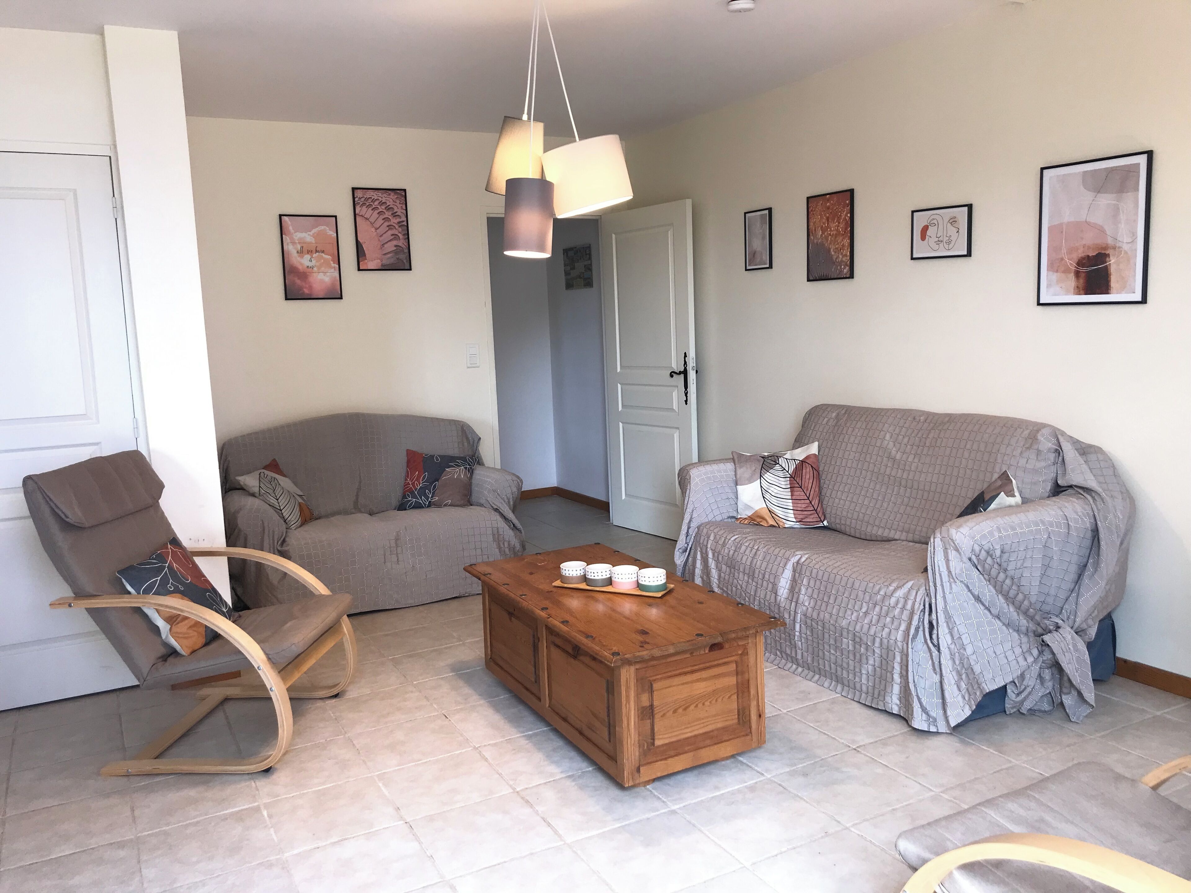 Uma sala de estar com dois sofás, uma mesa de centro de madeira e uma cadeira de balanço.