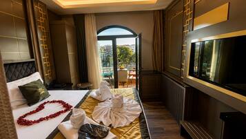 Quarto de hotel com cama, televisão e vista da cidade.