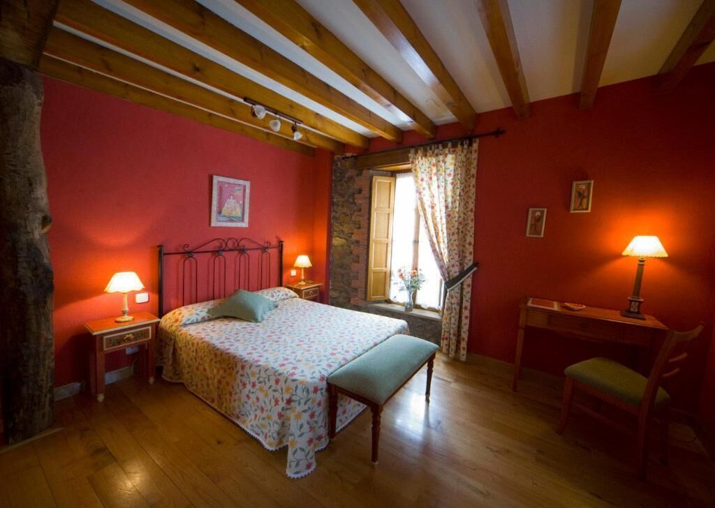 Quarto com cama, mesas de cabeceira, escrivaninha e uma cadeira.