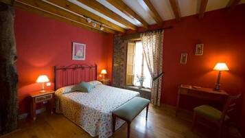 Quarto com cama, mesas de cabeceira, escrivaninha e uma cadeira.