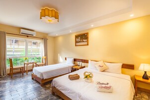 Quarto de hotel com duas camas, piso de madeira, janela com vista e luminária no teto.