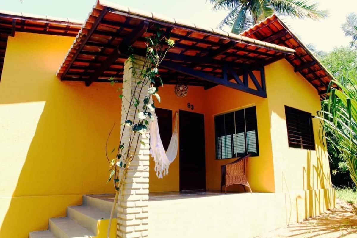 Um edifício amarelo com telhado vermelho, uma porta e uma janela.