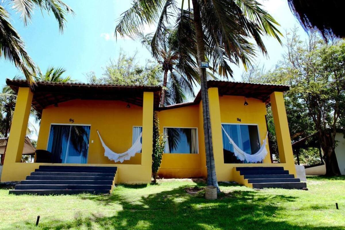 Um edifício amarelo com duas entradas distintas, cada uma com um conjunto de degraus até uma porta.