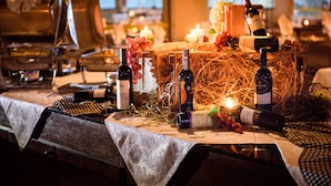 Mesa posta com garrafas de vinho, velas e elementos decorativos, sugerindo um ambiente de jantar romântico ou formal.
