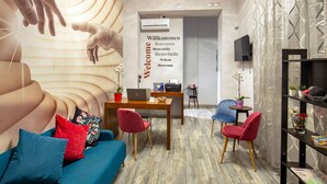 Uma área de recepção moderna com uma parede curva, um letreiro de boas-vindas, uma mesa com um laptop e duas cadeiras.