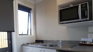 Uma cozinha compacta com armários brancos, micro-ondas embutido, pia e lava-louças.
