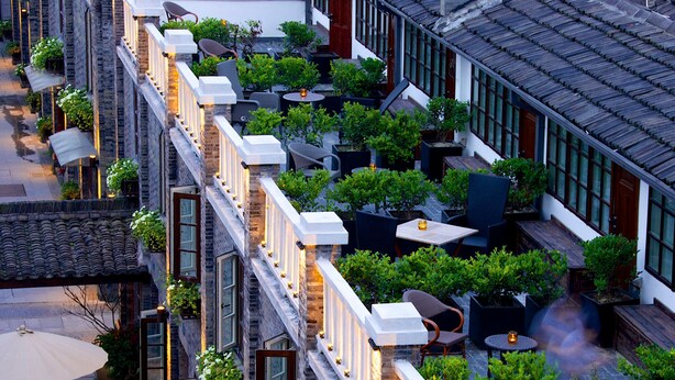 Terraço no telhado com área de estar externa, plantas em vasos e vista para a cidade.