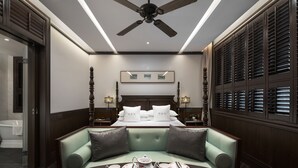 Quarto de hotel com uma cama grande, um sofá, uma mesa de jantar com chá e um ventilador de teto.