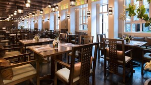 Um restaurante amplo, com pé-direito alto, várias mesas e cadeiras.