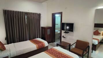 Quarto de hotel com duas camas, televisão, escrivaninha e uma cadeira.