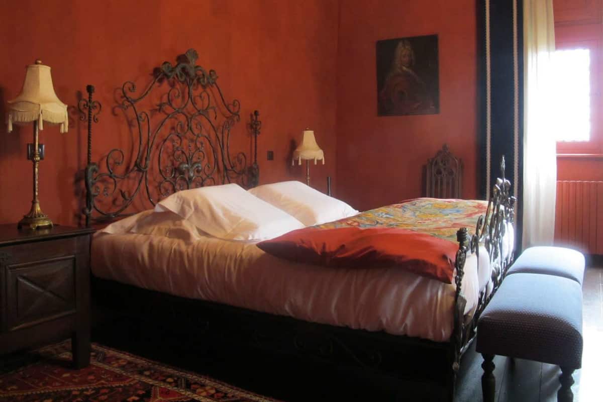 Quarto com cama, duas mesinhas de cabeceira, um criado-mudo e um quadro na parede.