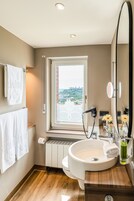 Uma casa de banho moderna com uma pia grande, um secador de cabelo, um espelho e uma janela com vista para a cidade.
