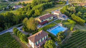 Vista aérea de uma propriedade com piscina, vários edifícios e vegetação ao redor.