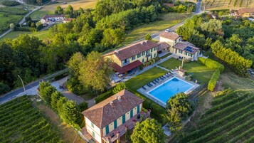Vista aérea de uma propriedade com piscina, vários edifícios e vegetação ao redor.