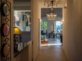Um corredor com cozinha moderna, mesa de jantar e lustre.