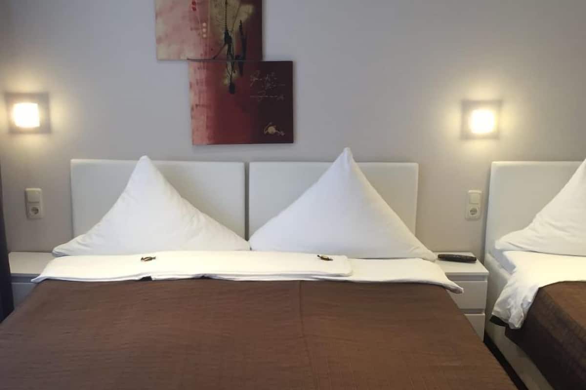 Quarto de hotel com uma cama grande, duas mesinhas de cabeceira e obras de arte fixadas na parede.