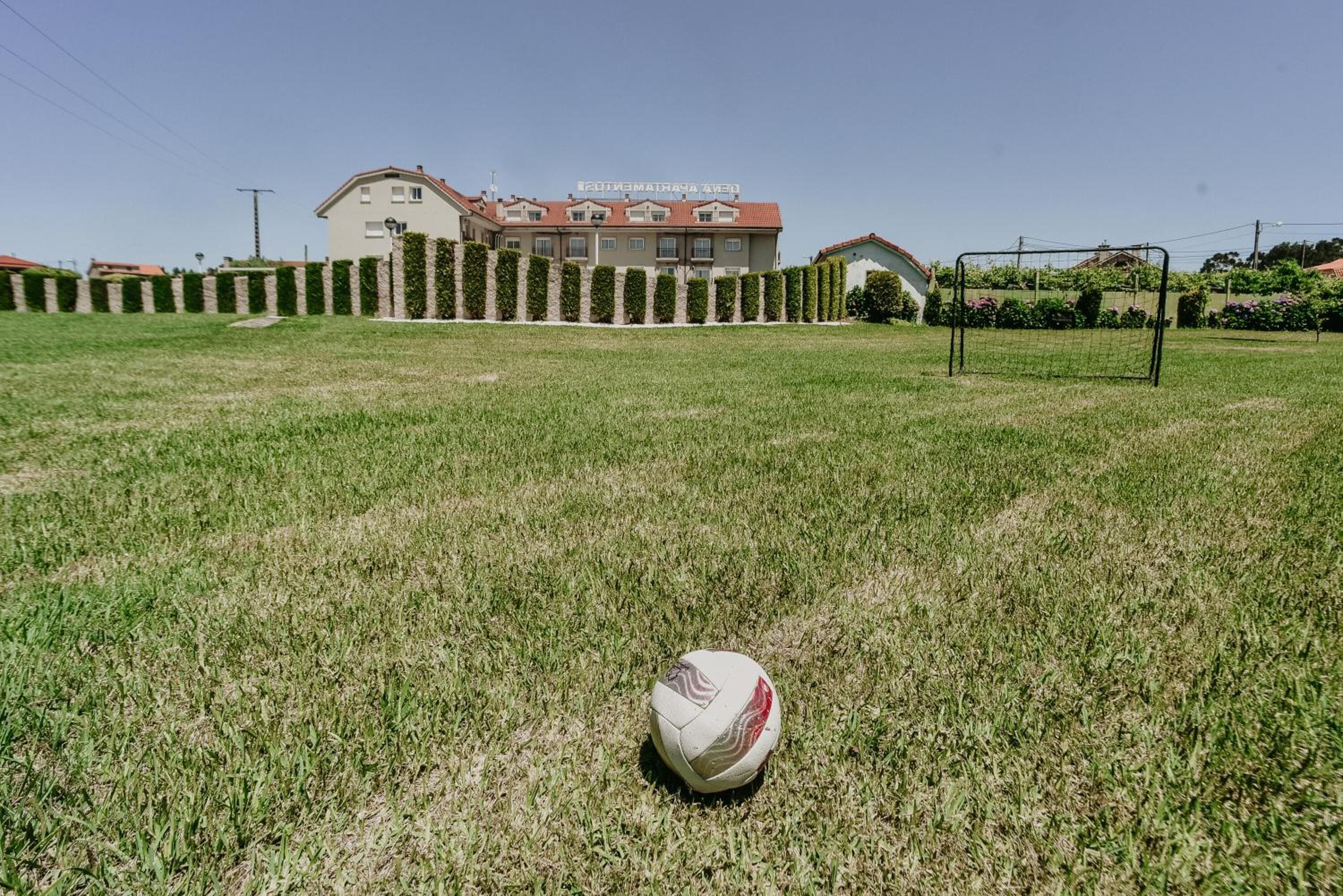 Um campo de futebol com um gol e um edifício ao fundo.