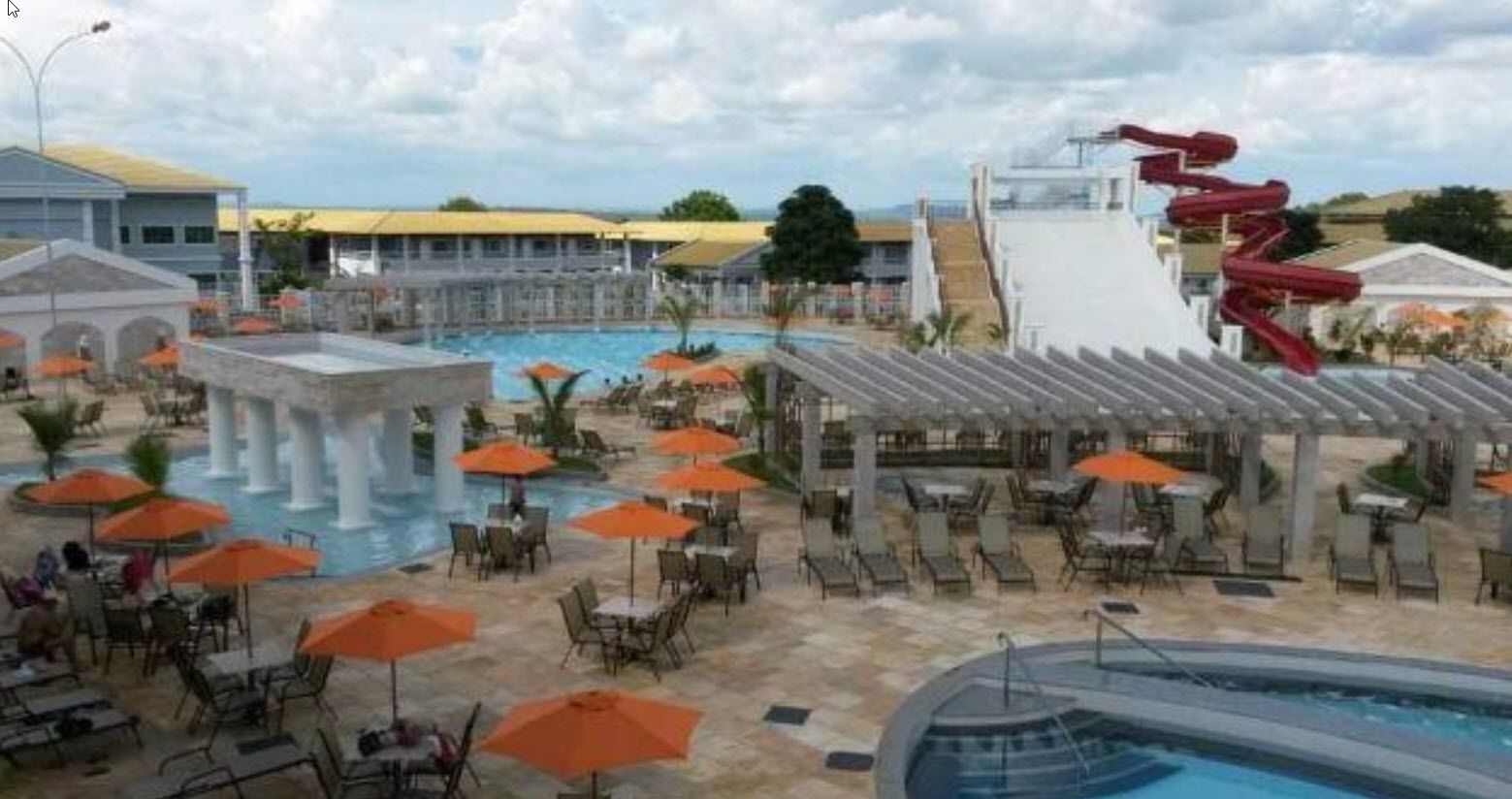 Uma área de piscina com várias piscinas, espreguiçadeiras e guarda-sóis.
