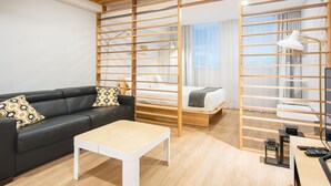 Quarto moderno com sofá de couro preto, estrutura de cama de madeira, mesa de cabeceira branca e escrivaninha com abajur.