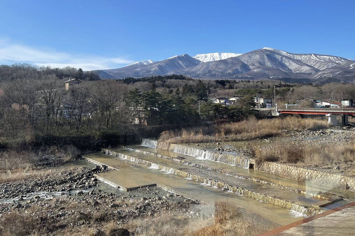 Paisagem montanhosa com uma ponte, um pequeno edifício e vários canais de água.