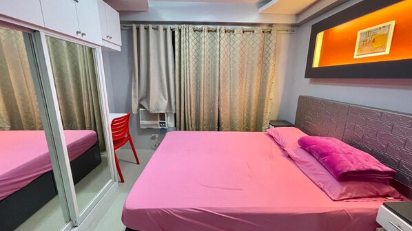 Quarto com cama, guarda-roupa, cadeira e cortina.