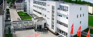 Um edifício moderno com um pátio central, vários andares e bandeiras vermelhas ao lado direito.