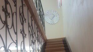 Escadaria com carpete, grades de metal decoradas e espelho ornamental fixado na parede.