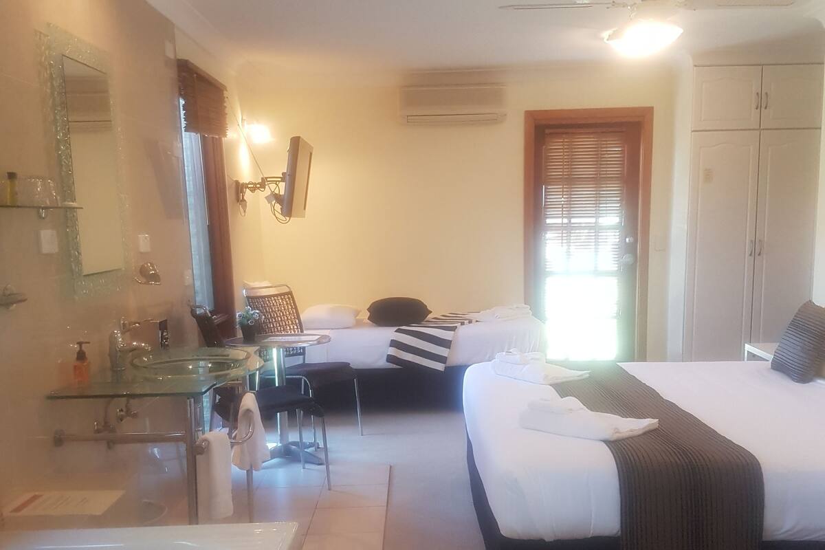 Quarto de hotel com uma cama grande, uma cama extra, área de estar, banheira e guarda-roupa.