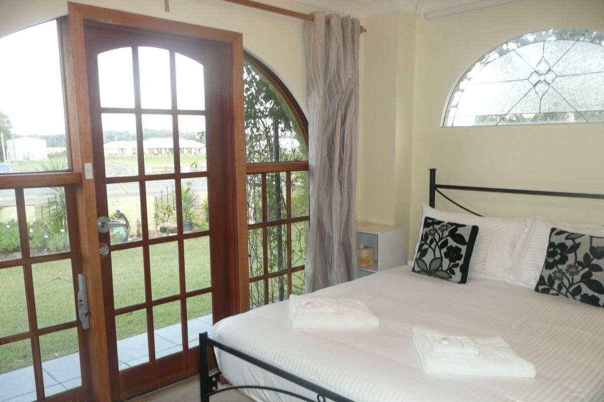 Um quarto com uma cama, uma janela com vista para o exterior e uma porta que dá para uma varanda.