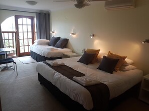 Quarto de hotel com duas camas, uma escrivaninha e vista pela janela grande.