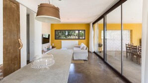 Uma sala de estar moderna com um sofá, uma mesa de centro e uma área de jantar com cadeiras e uma mesa.