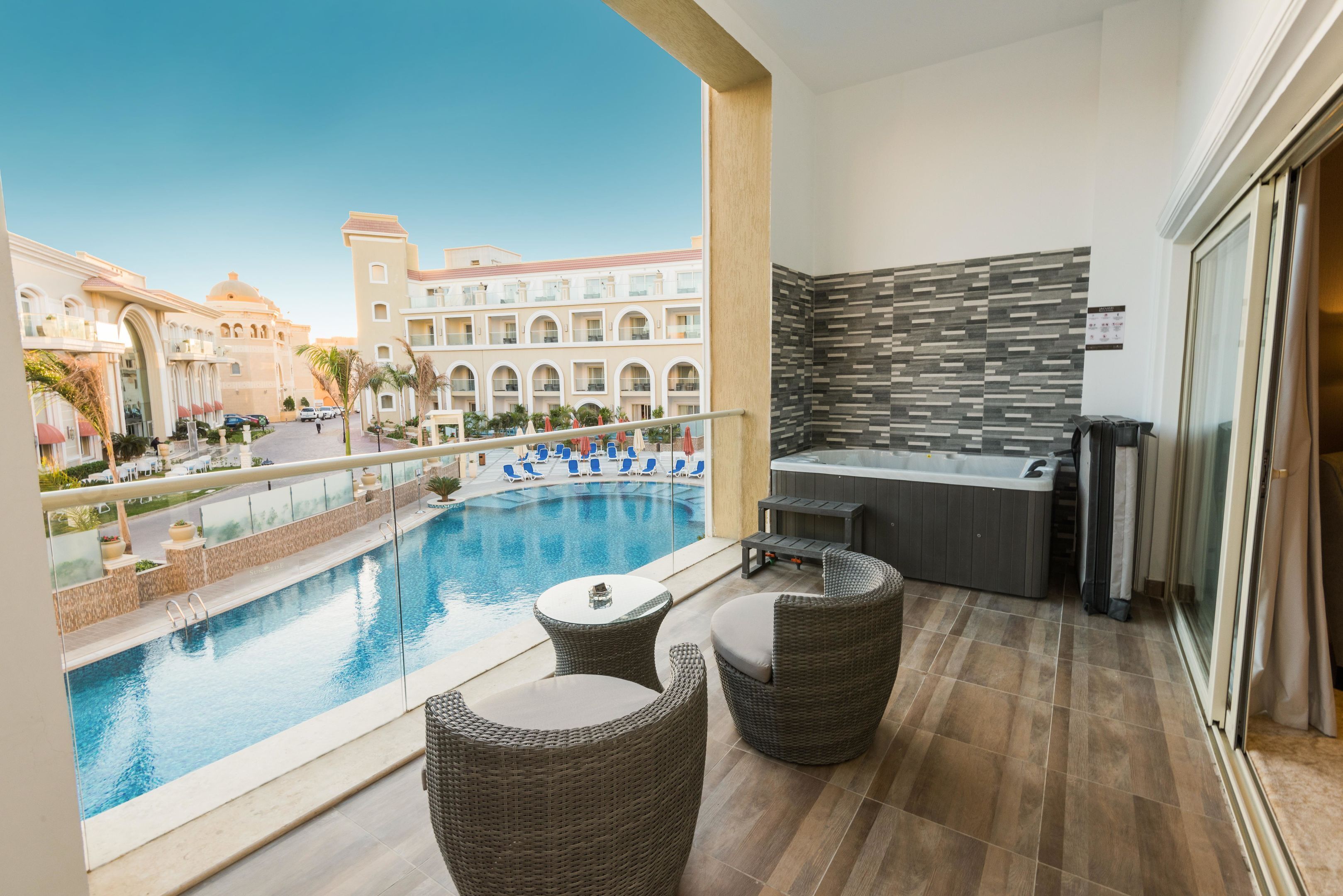 Varanda com piscina, mobiliário de vime e banheira de hidromassagem.