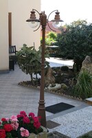 Um pátio com um candeeiro decorativo, um jardim de cactos e um chão em mosaico.