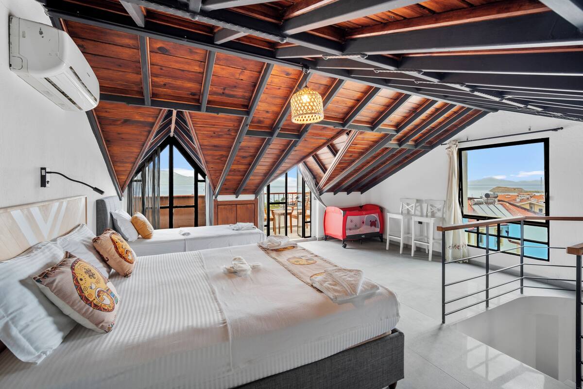 Quarto espaçoso com uma cama grande, vista para a cidade e varanda com guarda-corpo.