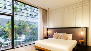 Quarto moderno com uma cama grande, vista para áreas verdes através de janelas do chão ao teto e design minimalista.