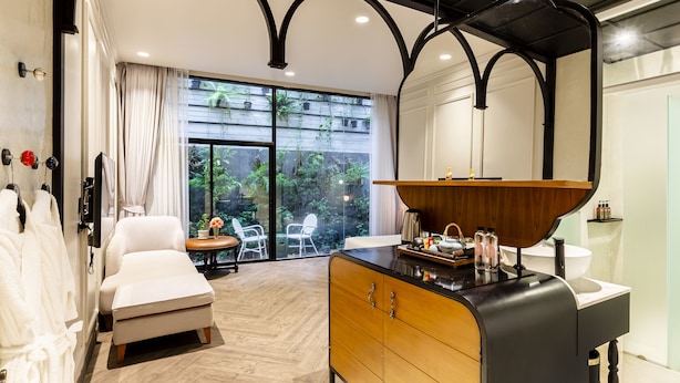 Uma casa de banho moderna com toucador de madeira, um espelho grande e vista para o verde lá fora.
