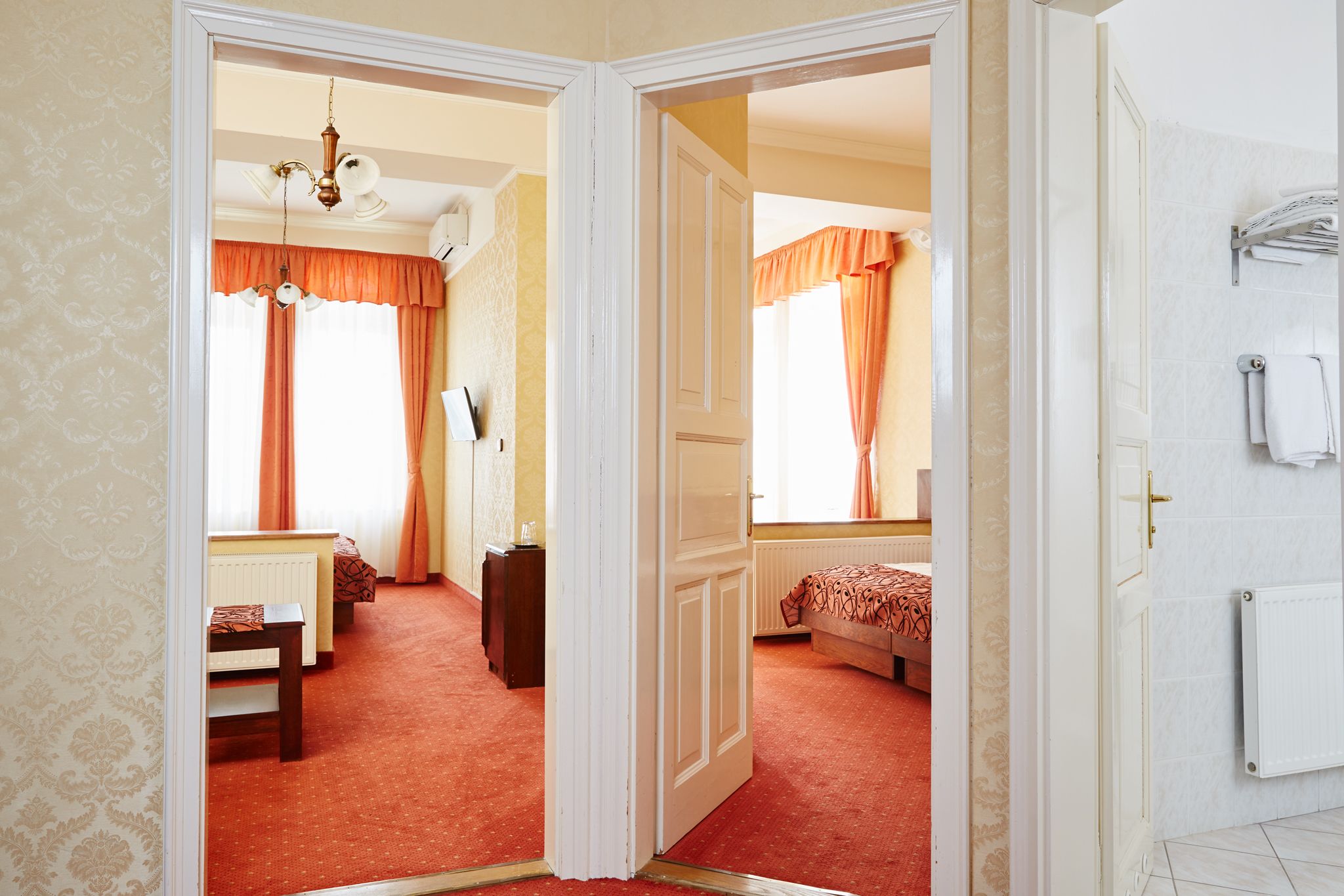 Quarto com cama, cadeira, radiador e janela com cortinas.