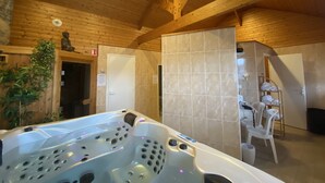 Interior de uma cabana de madeira com hidromassagem, uma estátua e um espaço com chuveiro.