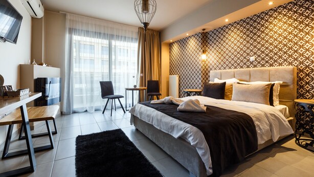 Quarto de hotel moderno com uma cama grande, uma escrivaninha com cadeira, uma televisão e uma parede estampada.