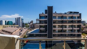Um edifício com vários andares, uma torre central, grandes janelas e um terraço no telhado.