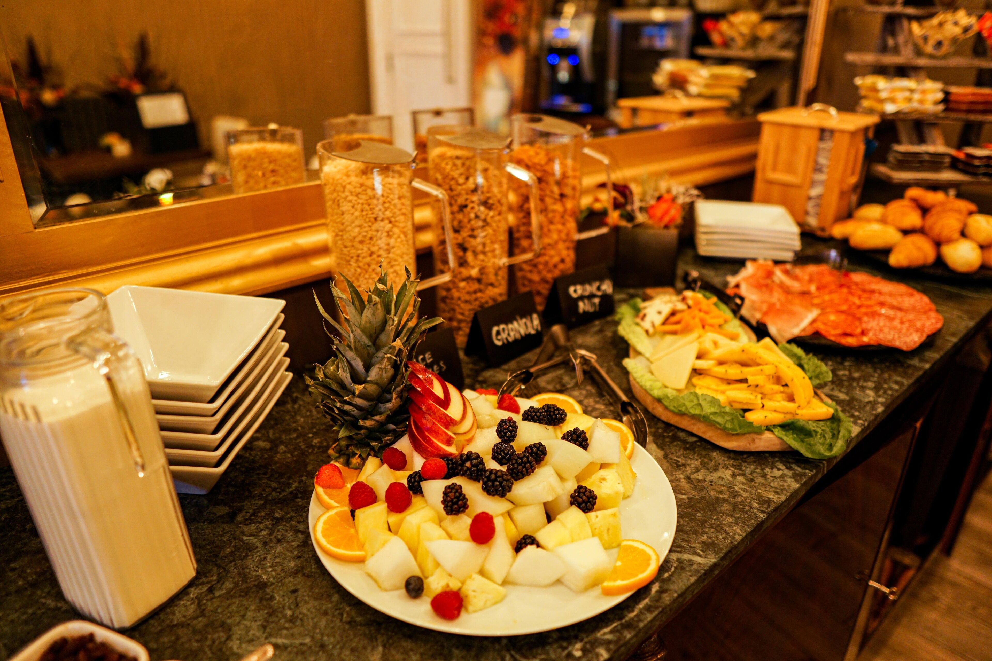 Buffet com diversos alimentos, incluindo frutas, nozes e sanduíches.
