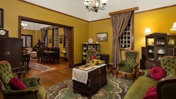 Uma sala de estar tradicional com um sofá verde, poltronas, uma mesa de centro de madeira e um candelabro.