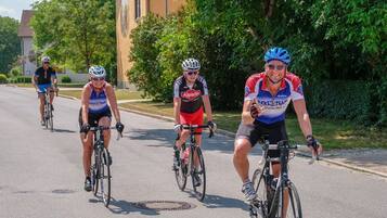 Três ciclistas pedalando em uma estrada pavimentada, com uma tampa de bueiro à vista.