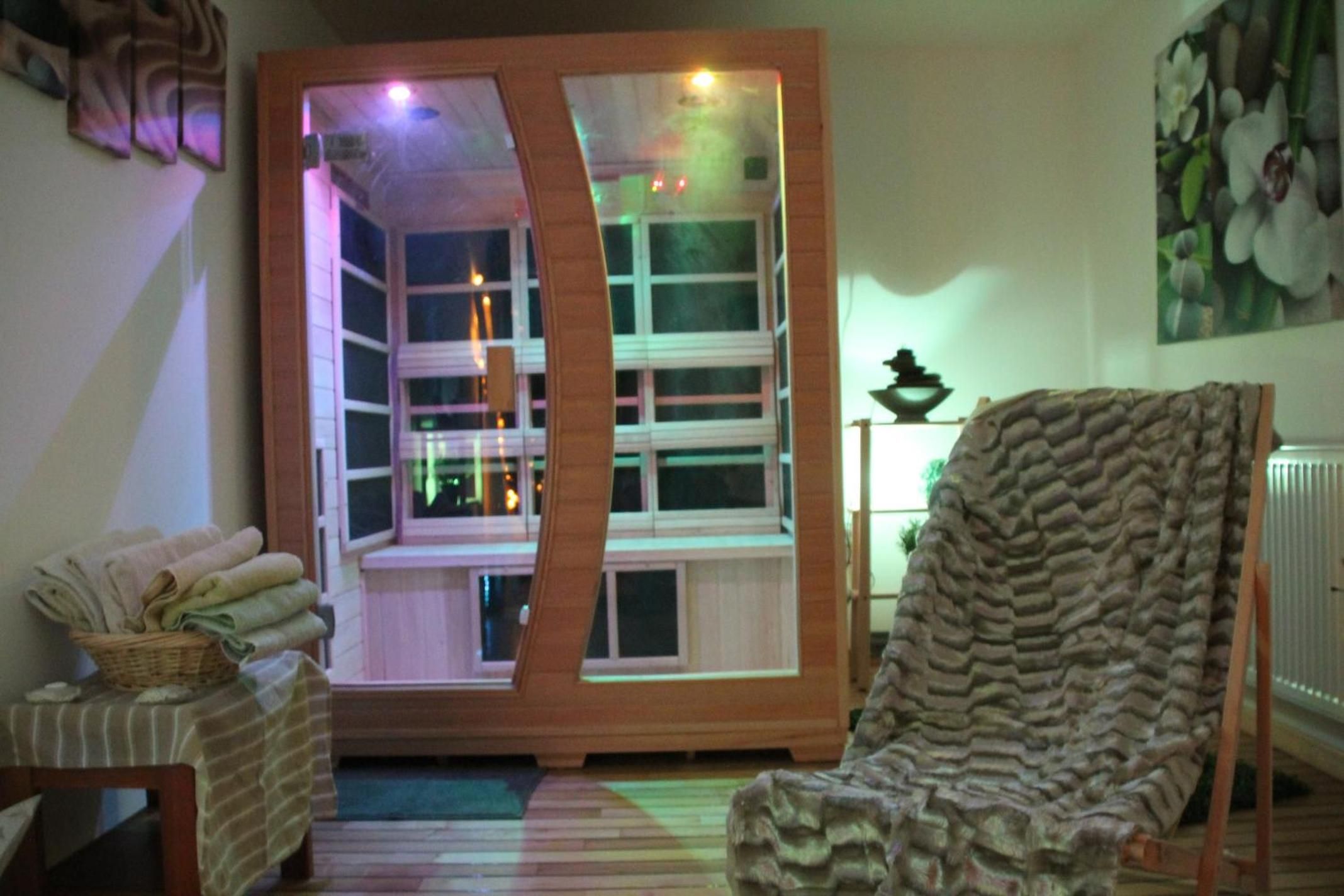 Quarto com uma janela grande, uma cadeira, um radiador e uma prateleira fixada na parede.
